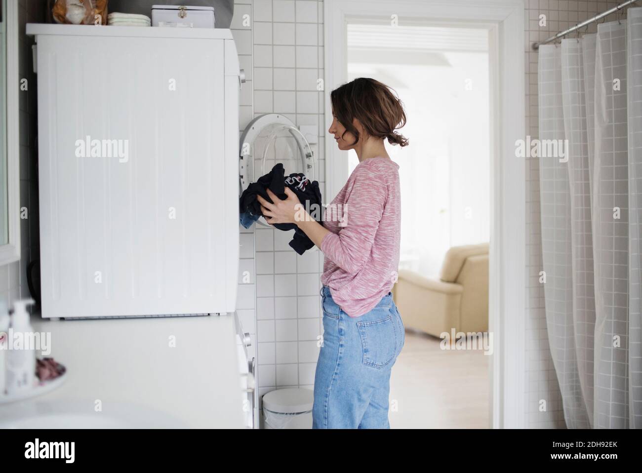 Side view of woman loading clothes in washing machine at home Stock ...