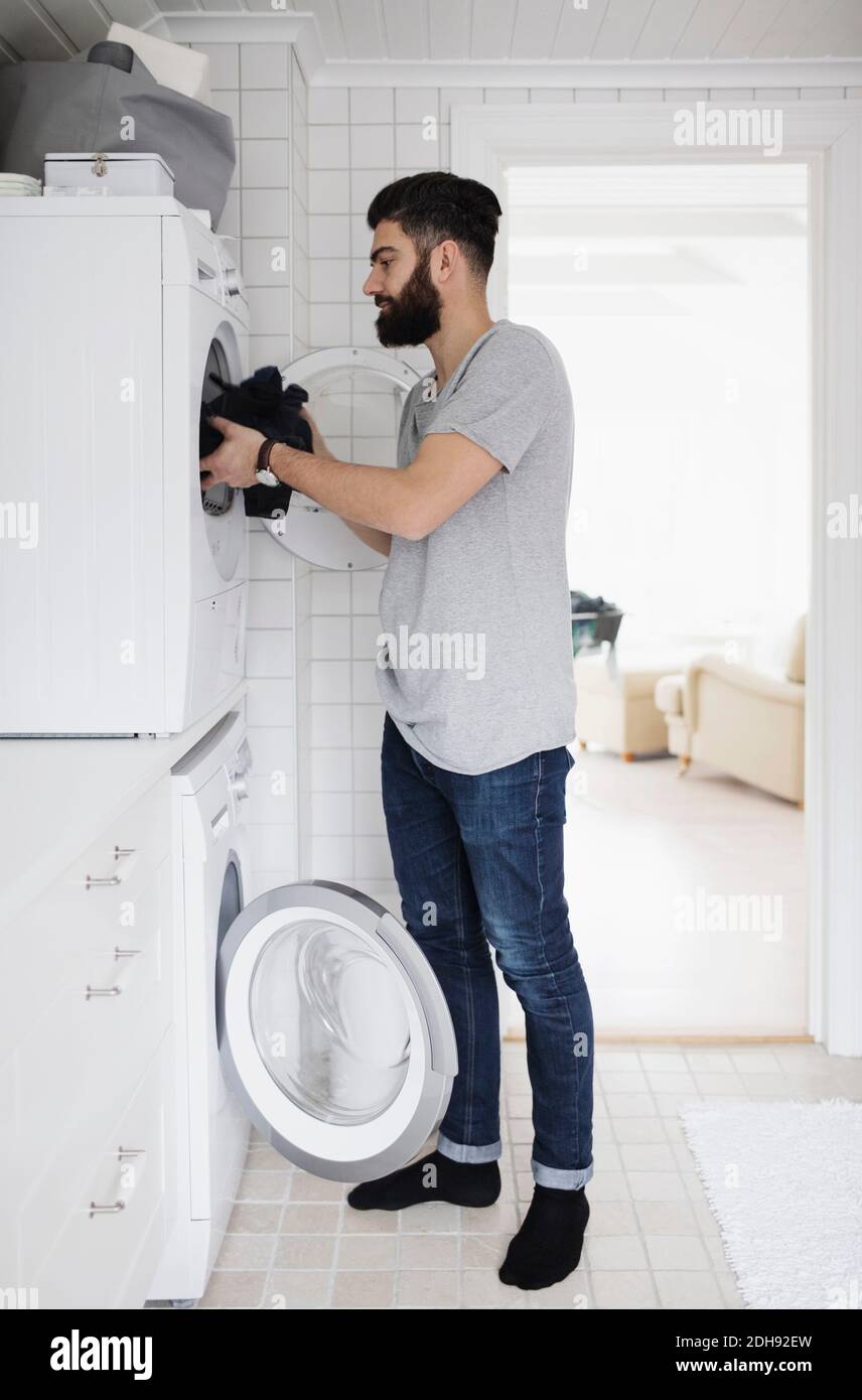 Side view of man loading clothes in washing machine at home Stock Photo ...