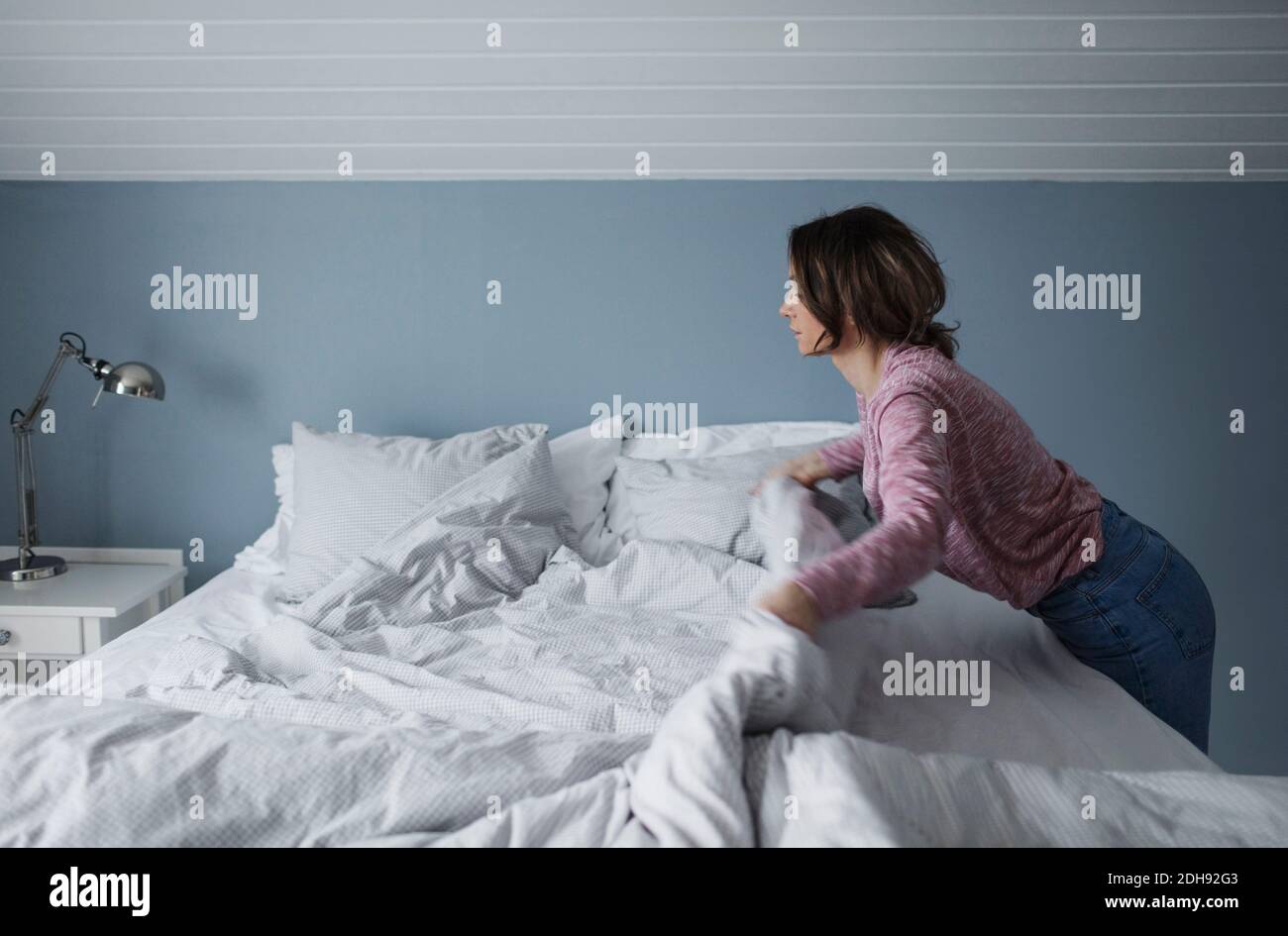 Side view of woman making bed at home Stock Photo - Alamy