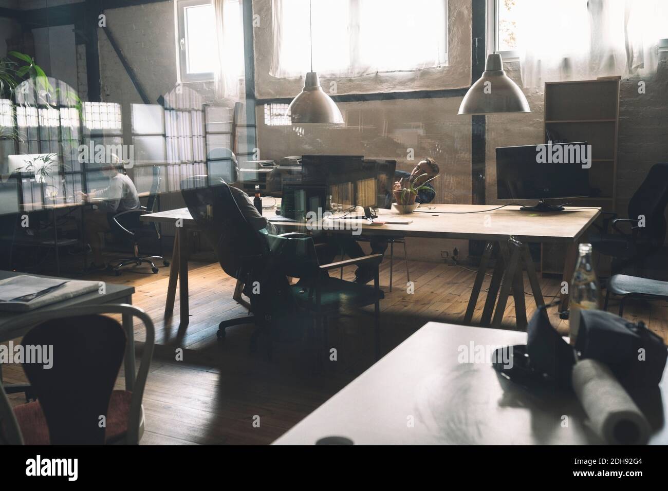 Business colleagues sitting at workplace seen through glass window ...