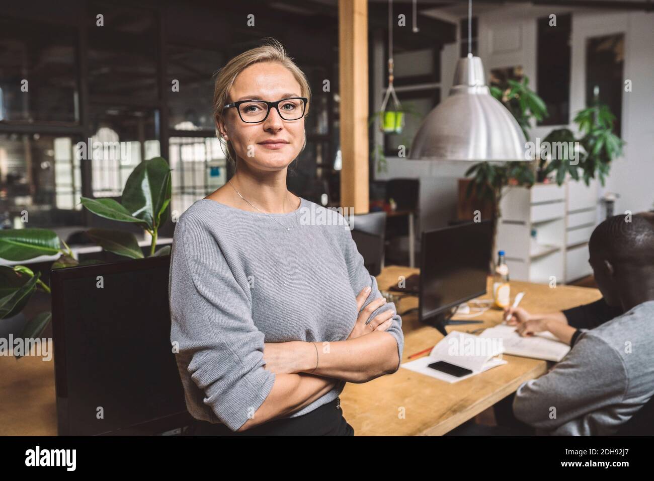 Portrait of confident freelancer with arms crossed at workplace Stock ...