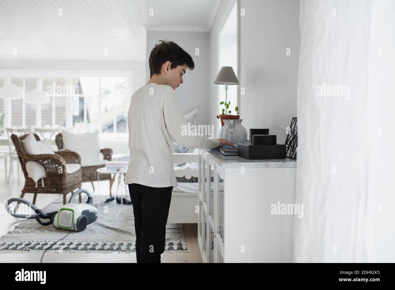 Boy cleaning cabinet in living room at home Stock Photo - Alamy