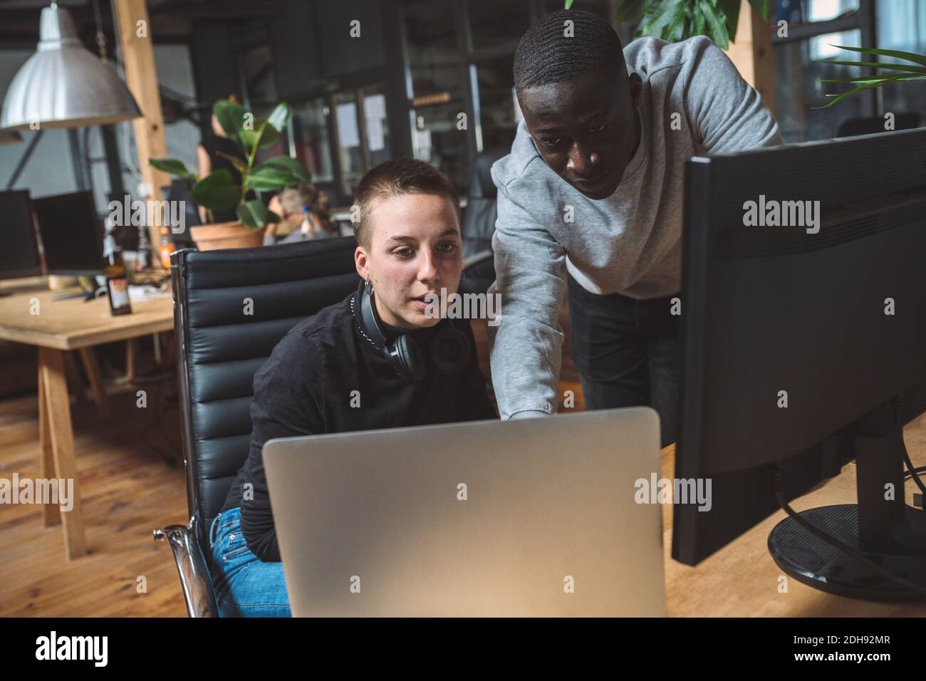 Computer programmer by female coworker using laptop at workplace Stock ...
