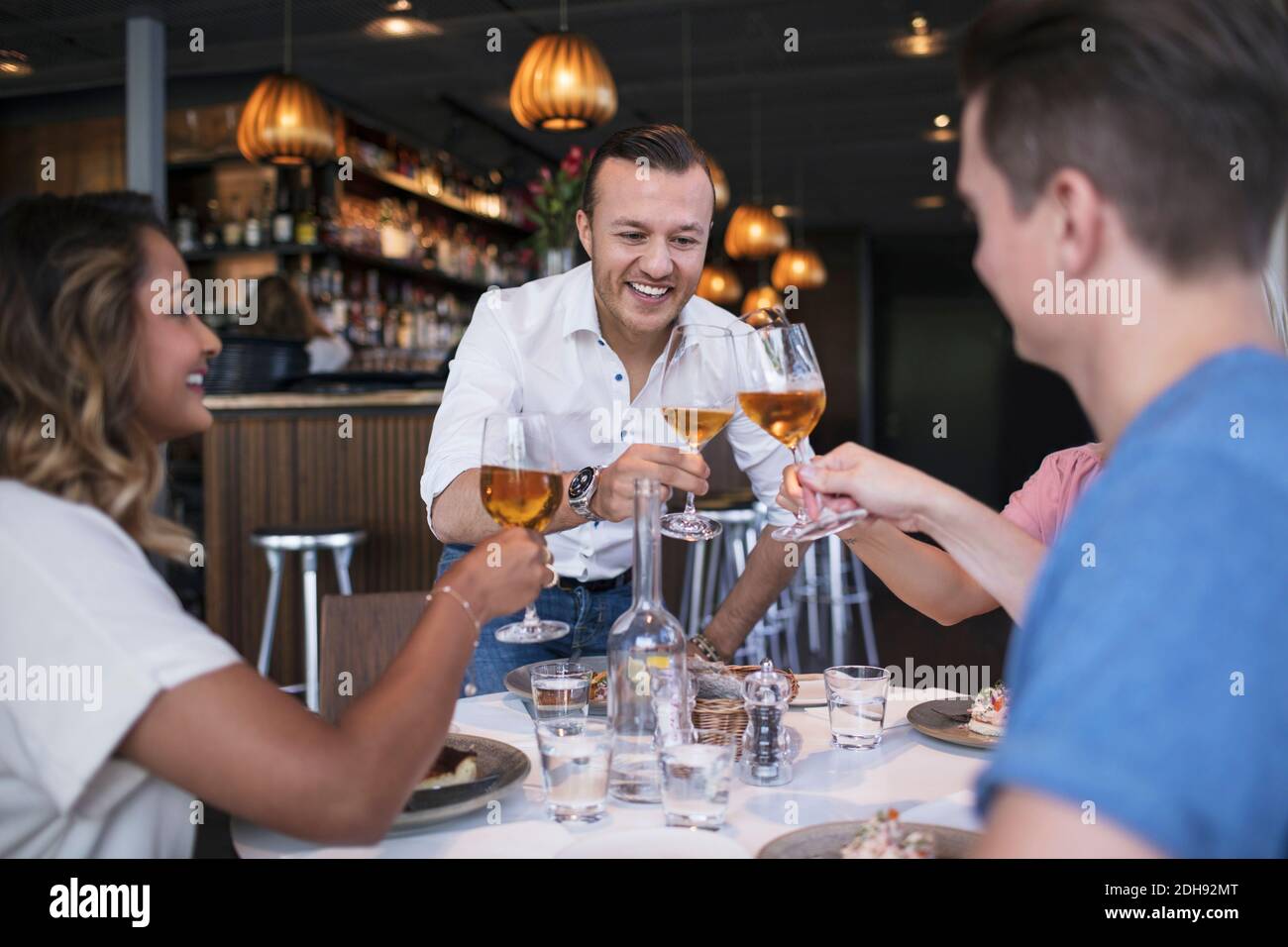 Happy colleagues raising toast during business lunch at restaurant ...