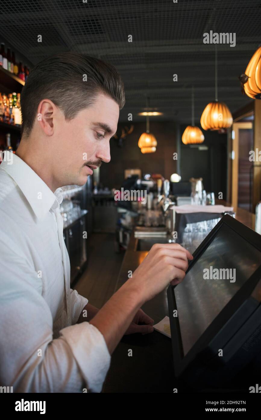Side view of owner using cash register at checkout in restaurant Stock ...