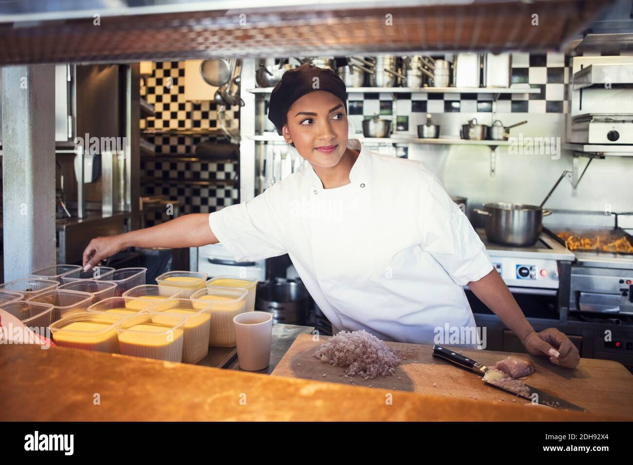 Female chef cooking while looking away at restaurant kitchen Stock ...
