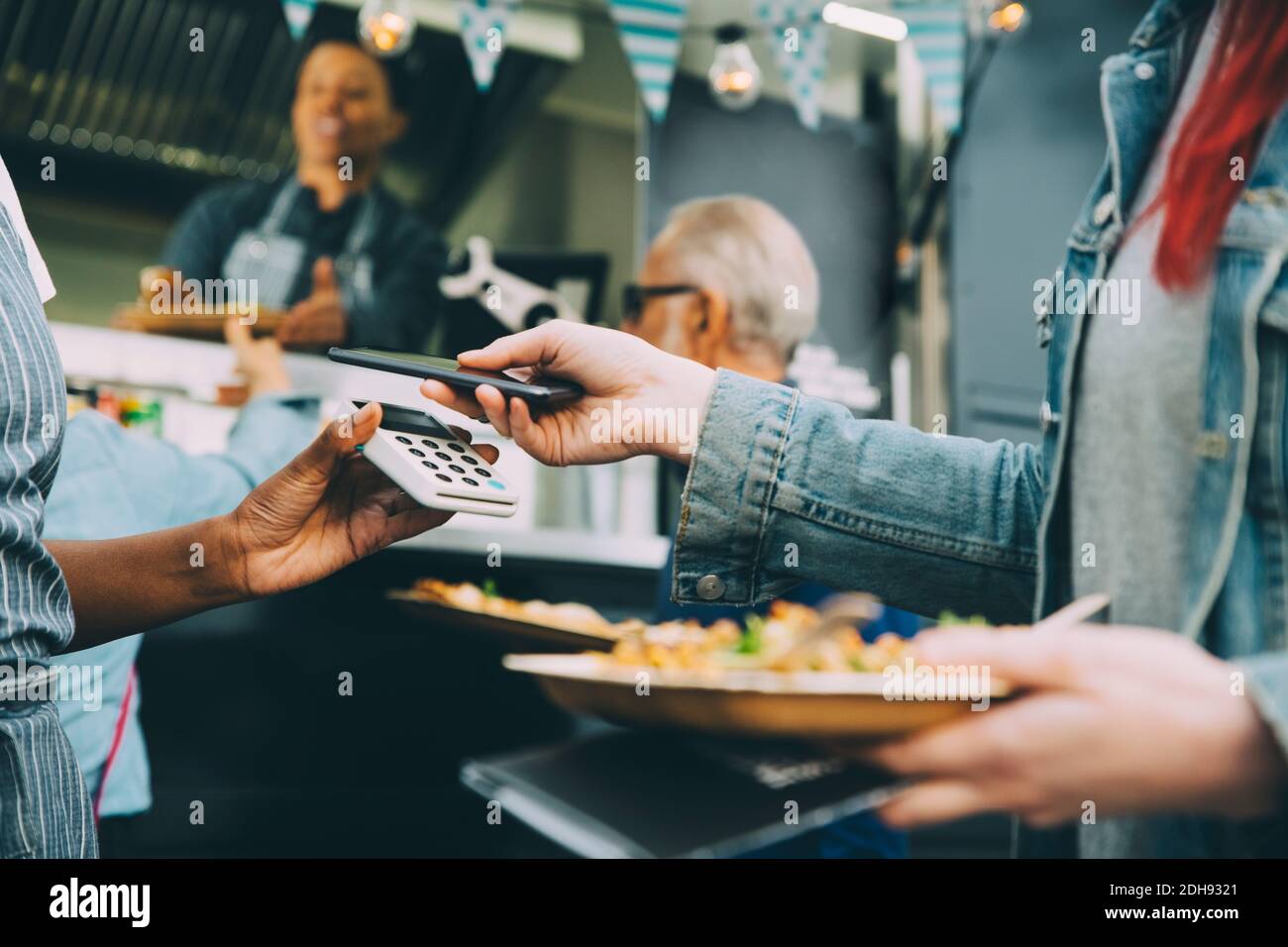 Midsection of customer paying through smart phone in city Stock Photo ...