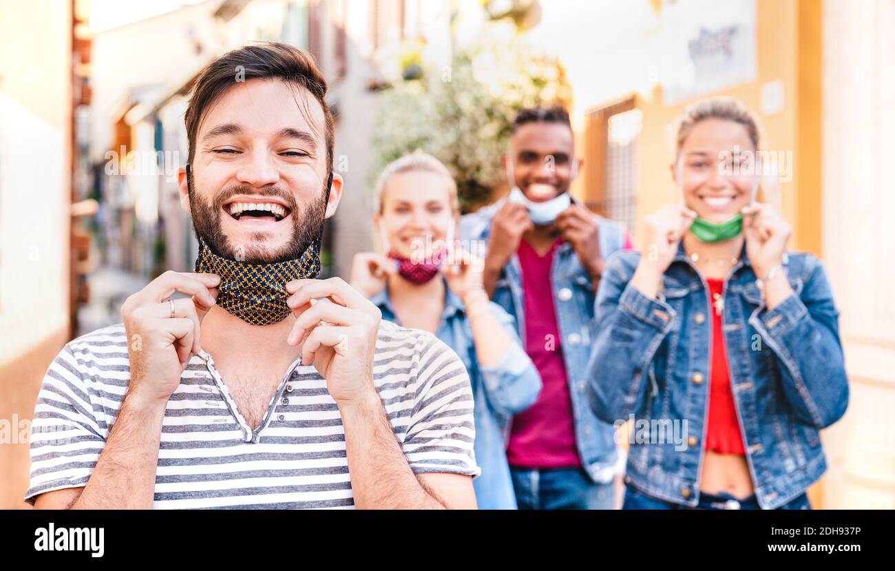 Happy friends smiling with opened face masks after lockdown reopening ...