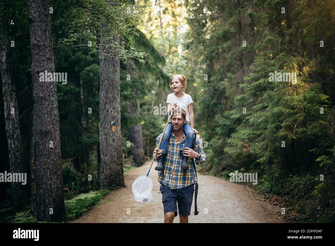 Father carrying daughter on shoulder while walking in forest Stock ...