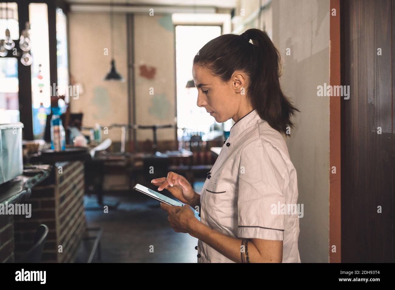 Side view of female chef using smart phone in restaurant Stock Photo ...