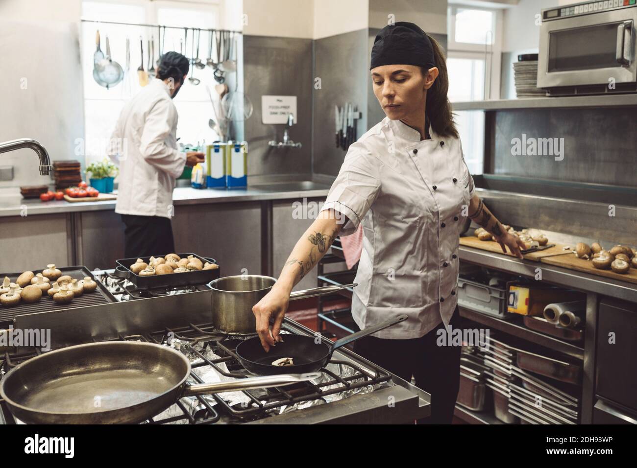 Male and female chefs preparing food in commercial kitchen Stock Photo ...