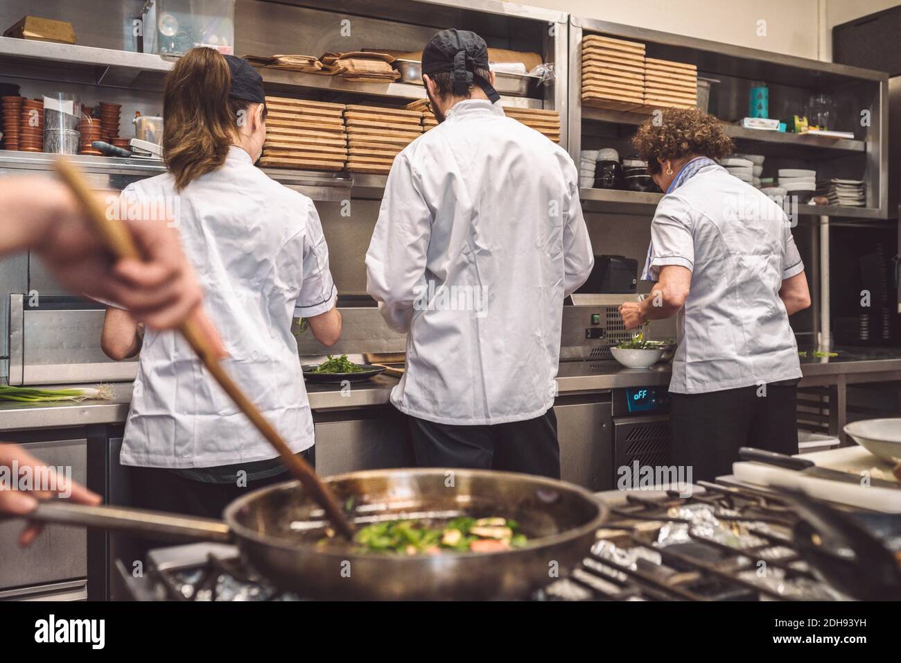 Rear view of chefs working on kitchen counter in restaurant Stock Photo ...