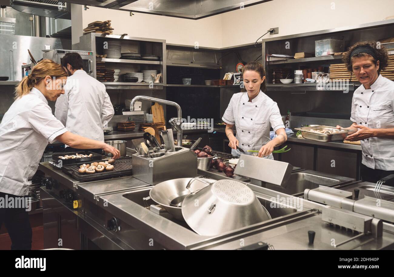 Chefs preparing food in commercial kitchen at restaurant Stock Photo ...