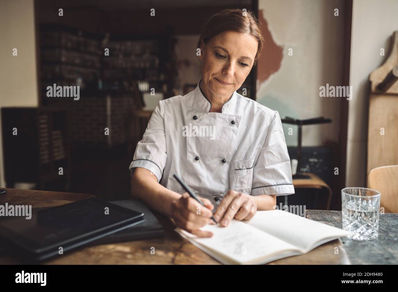 Mature chef writing in book at restaurant Stock Photo - Alamy