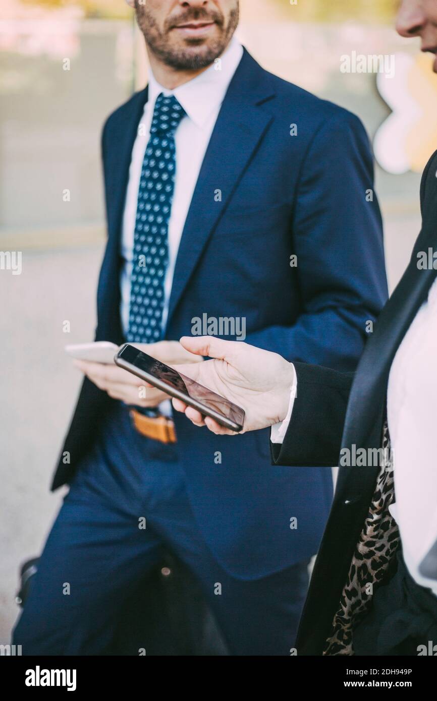Midsection of business colleagues with smart phone in city Stock Photo ...
