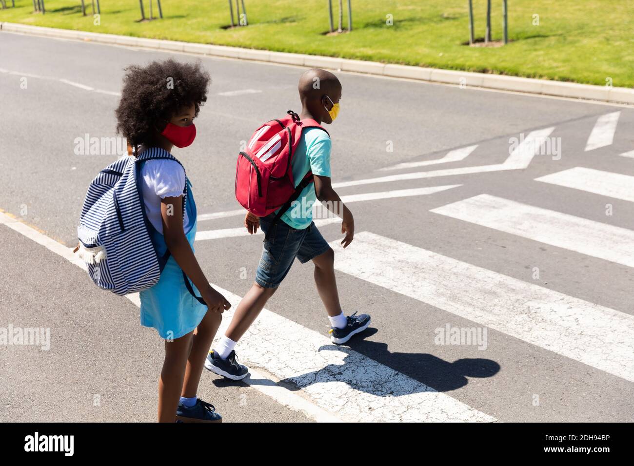 Two kids wearing face masks crossing the road Stock Photo - Alamy