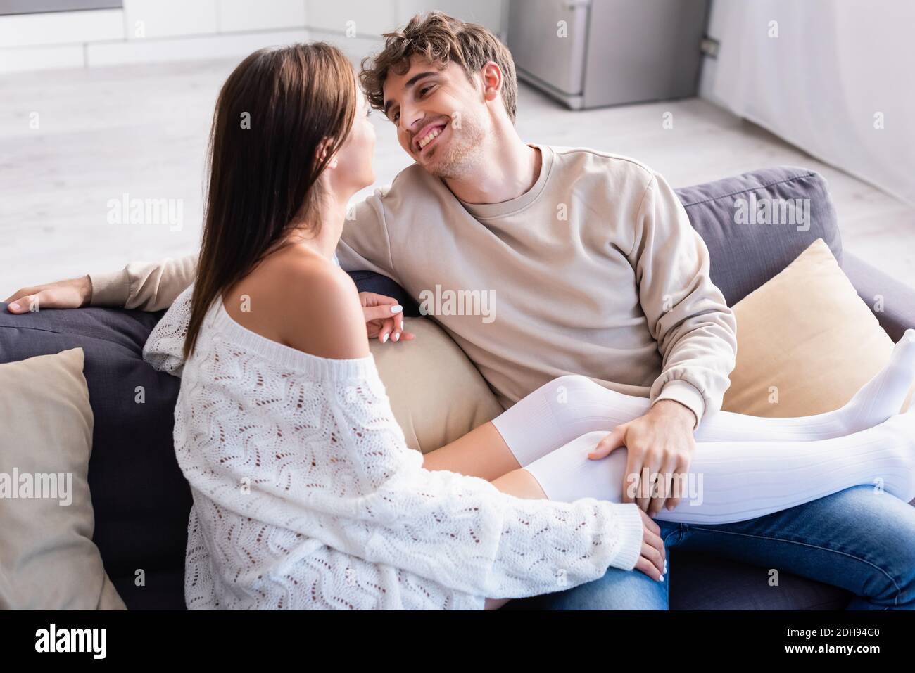 Smiling man touching legs of girlfriend in knee socks on couch Stock ...