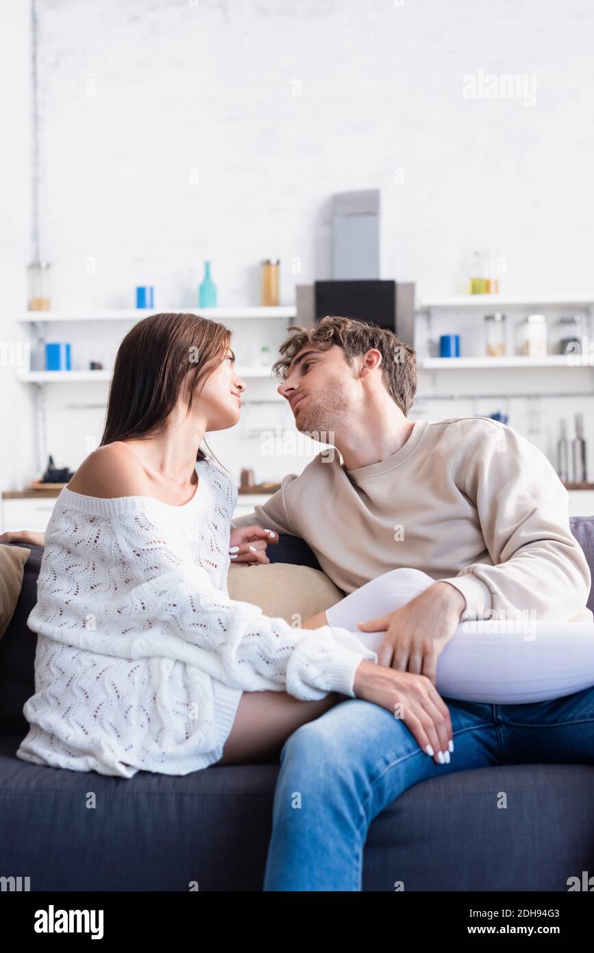 Young man touching legs of girlfriend in knee socks and knitted sweater ...