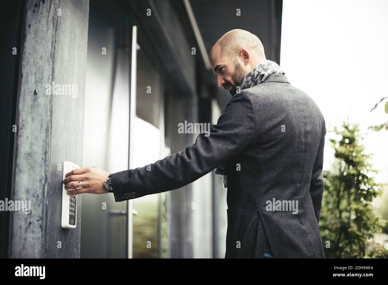 Side view of mid adult businessman entering keycode to open office door ...
