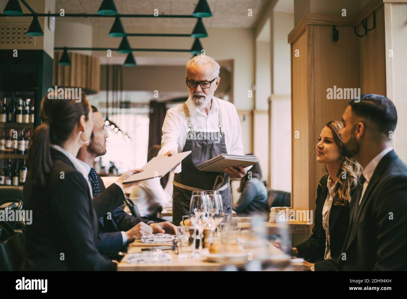 Waiter giving menu to business people in restaurant Stock Photo - Alamy