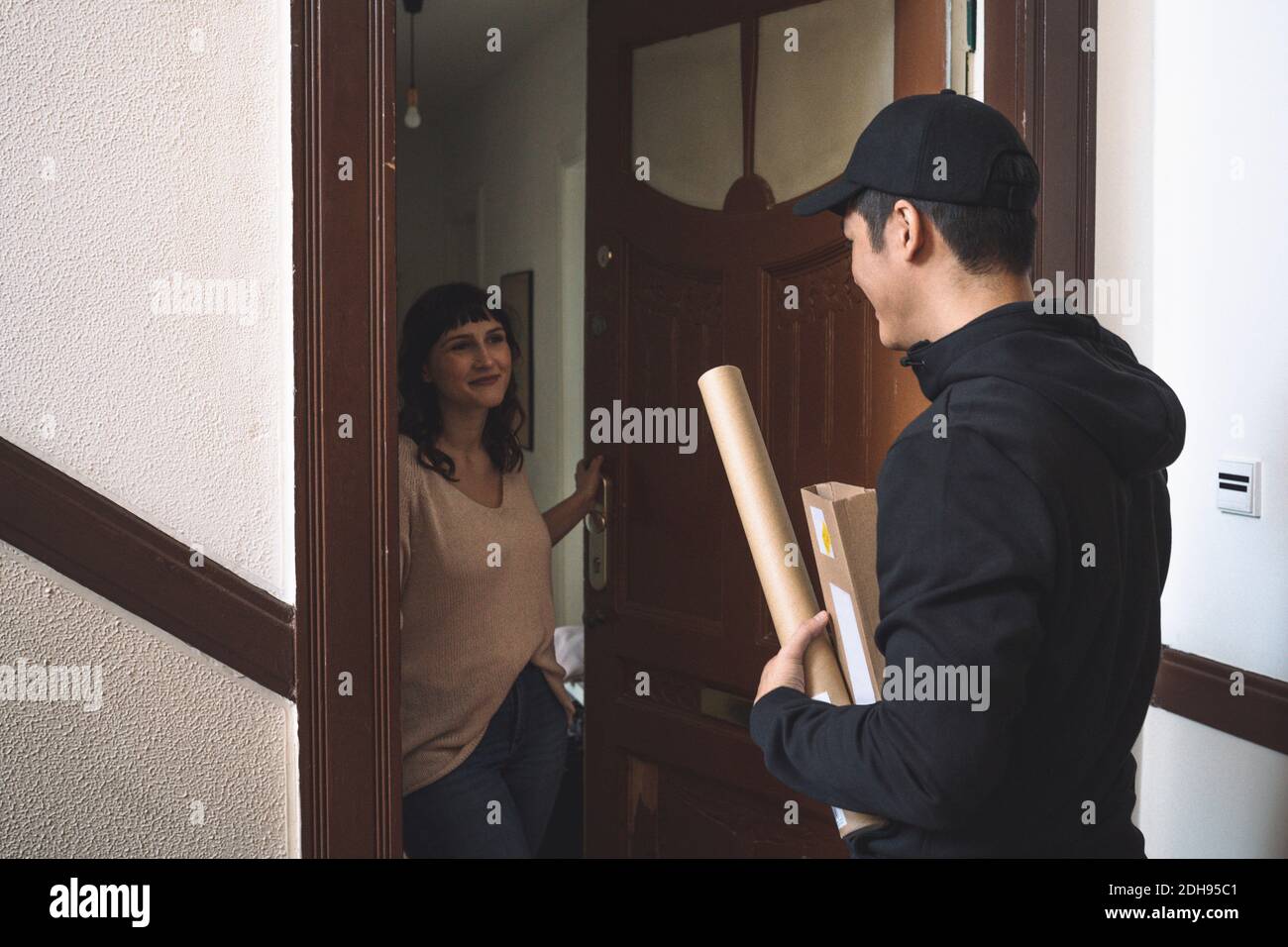 Smiling customer talking to delivery man at doorstep Stock Photo - Alamy