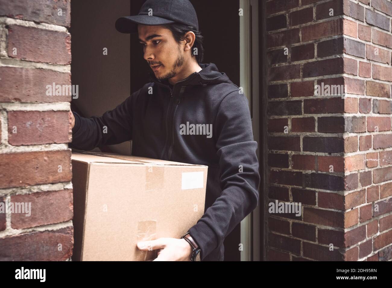 Delivery man with package standing in doorway Stock Photo - Alamy