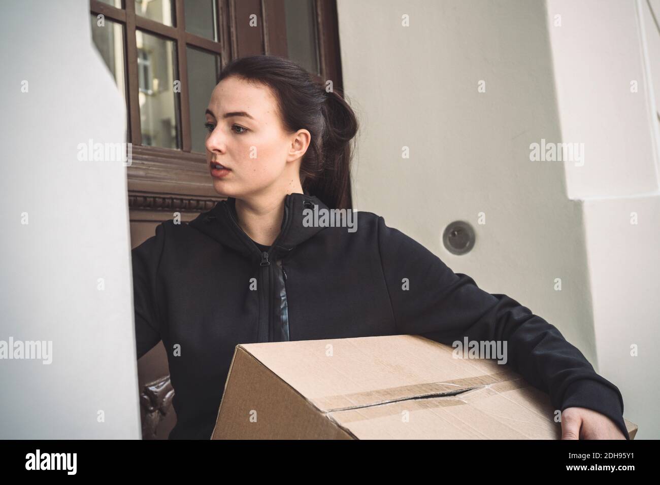 Delivery woman with package standing at doorstep Stock Photo - Alamy
