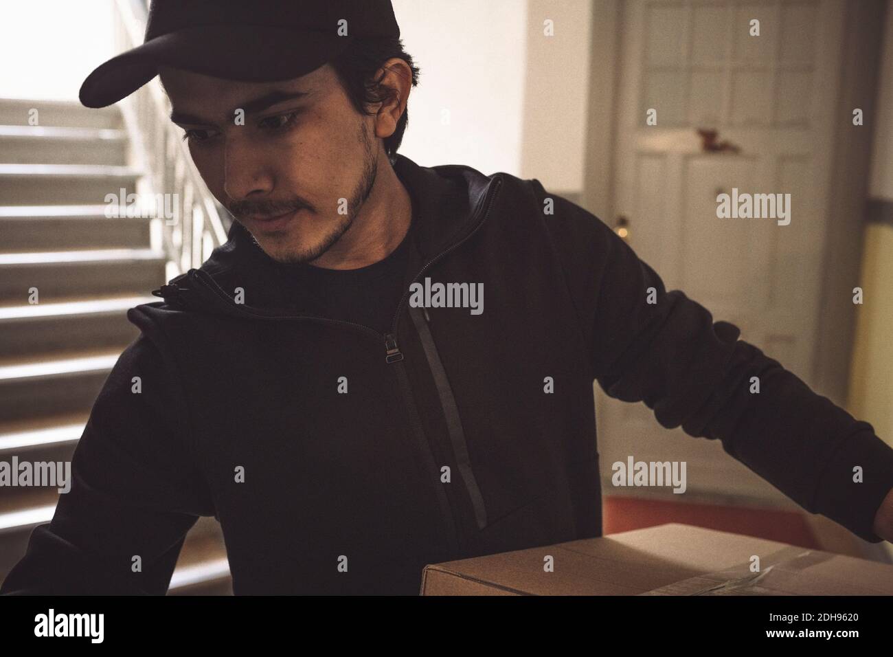 Confident delivery man with package making home delivery Stock Photo ...