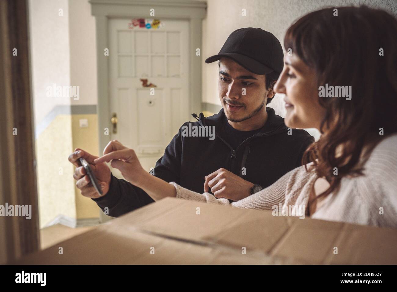 Female customer signing on mobile phone during package delivery Stock ...