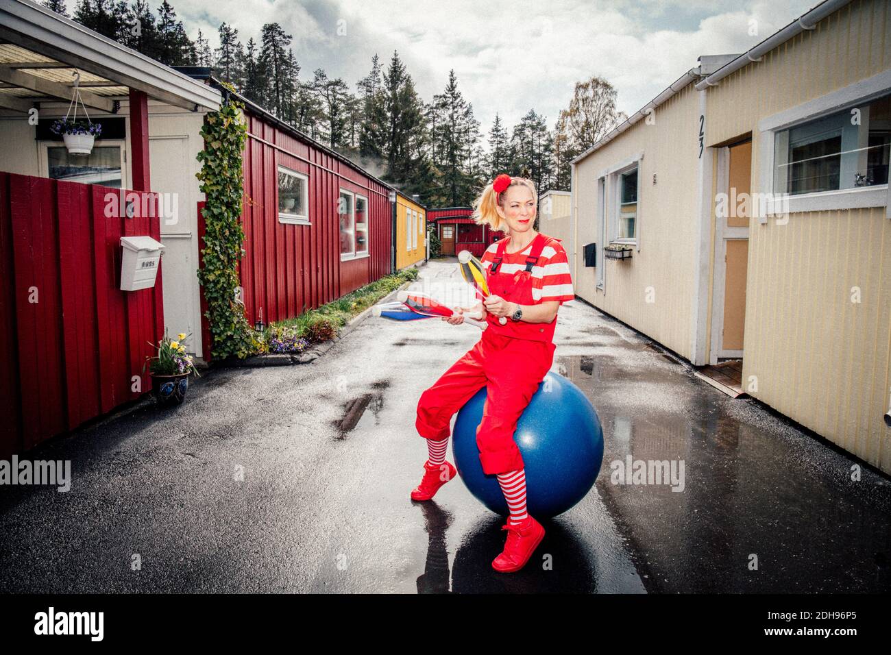 Woman with juggling pins looking away while sitting on fitness ball ...
