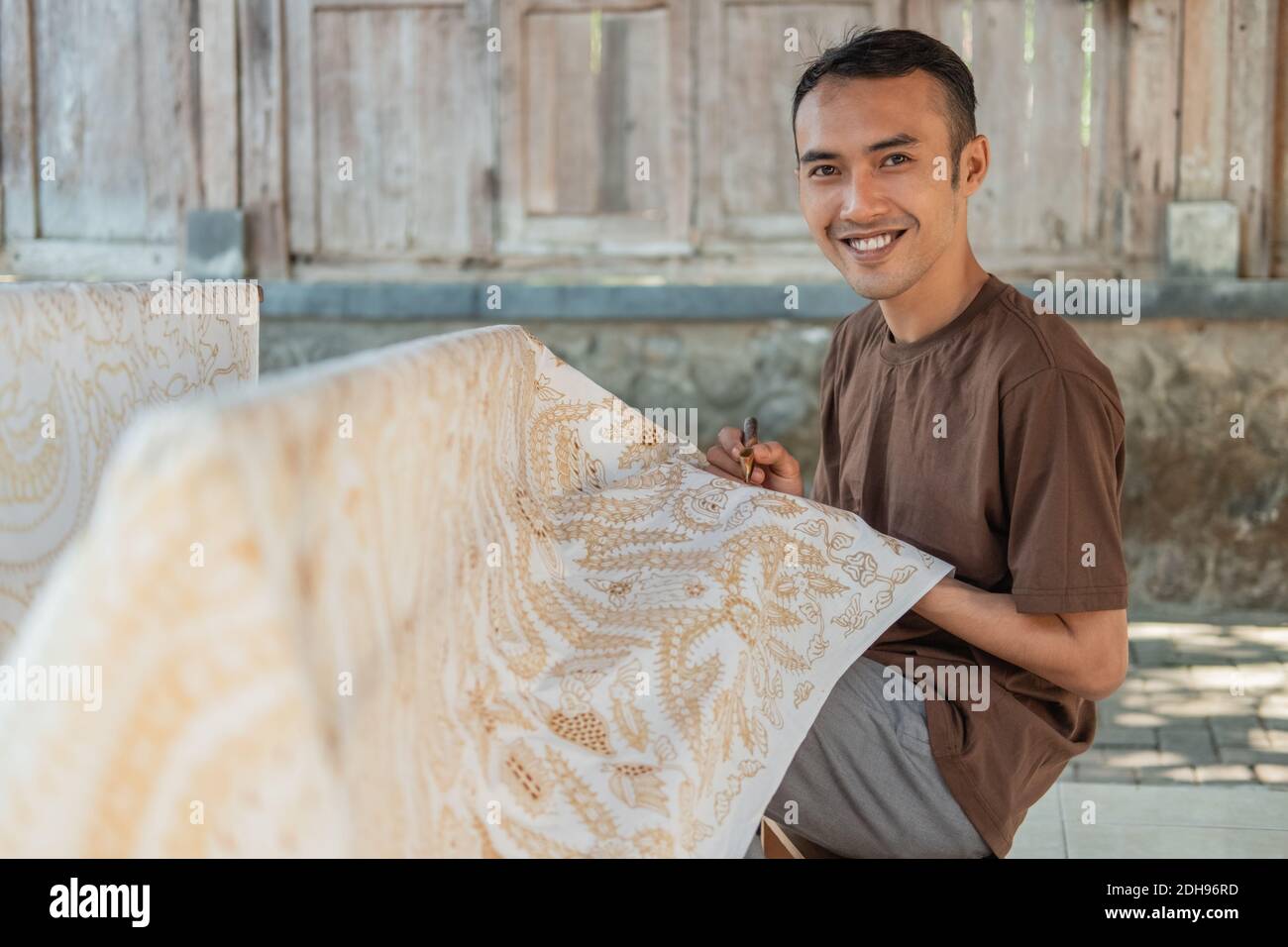 portrait of a worker drawing traditional indonesian batik on a white ...