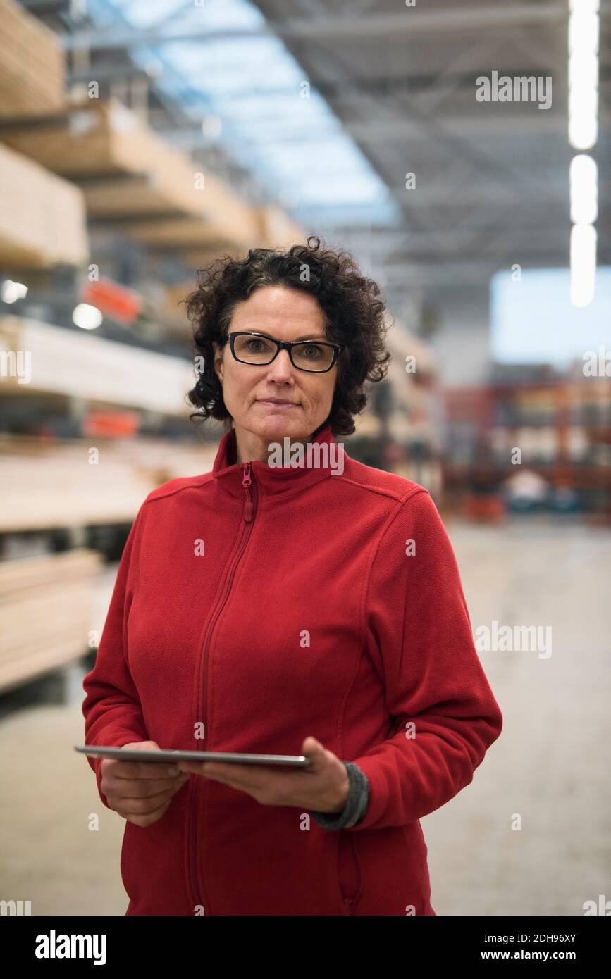 Portrait of confident female customer holding digital tablet while ...