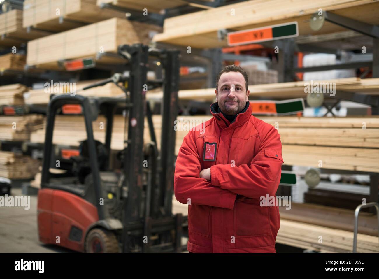 Portrait of confident salesman standing arms crossed in warehouse at ...