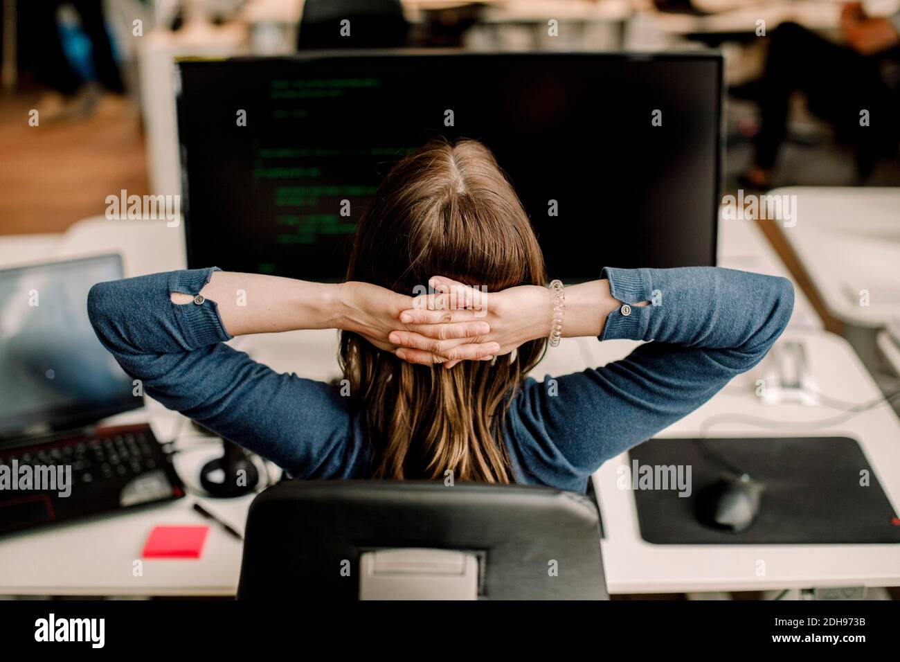 Rear view of entrepreneur sitting against computer at workplace Stock ...