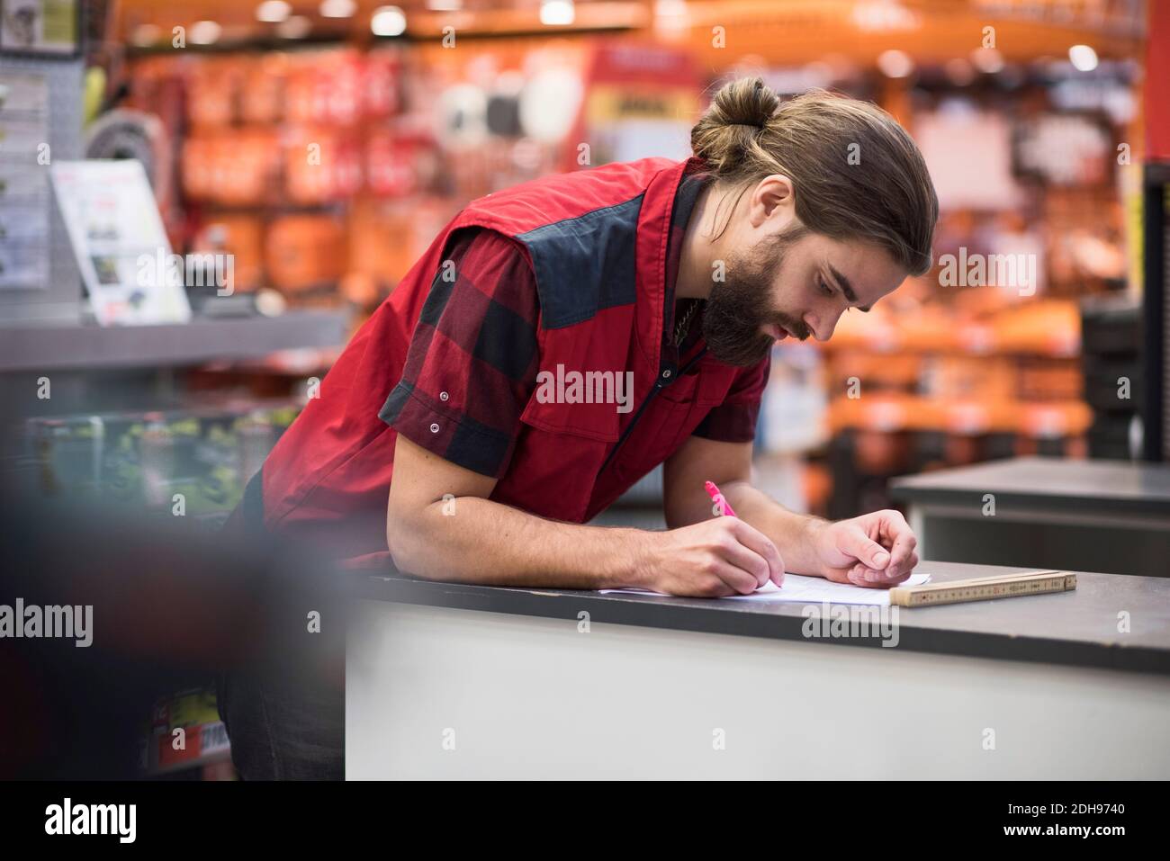 Salesman writing in book at hardware store Stock Photo - Alamy
