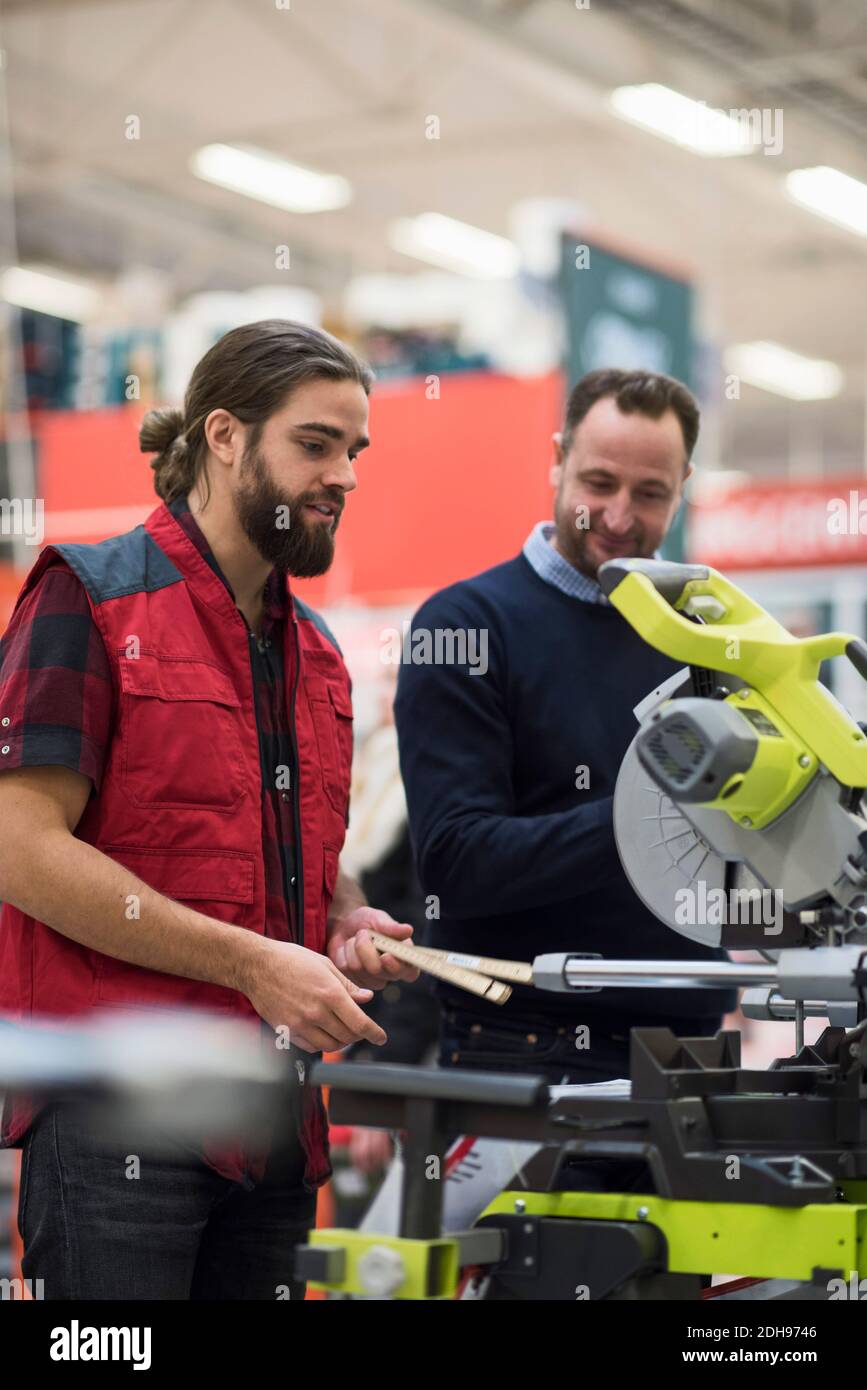 Salesman explaining machinery to male customer in hardware store Stock ...