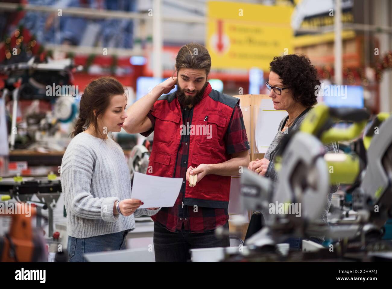 Salesman discussing with female customers in hardware store Stock Photo ...