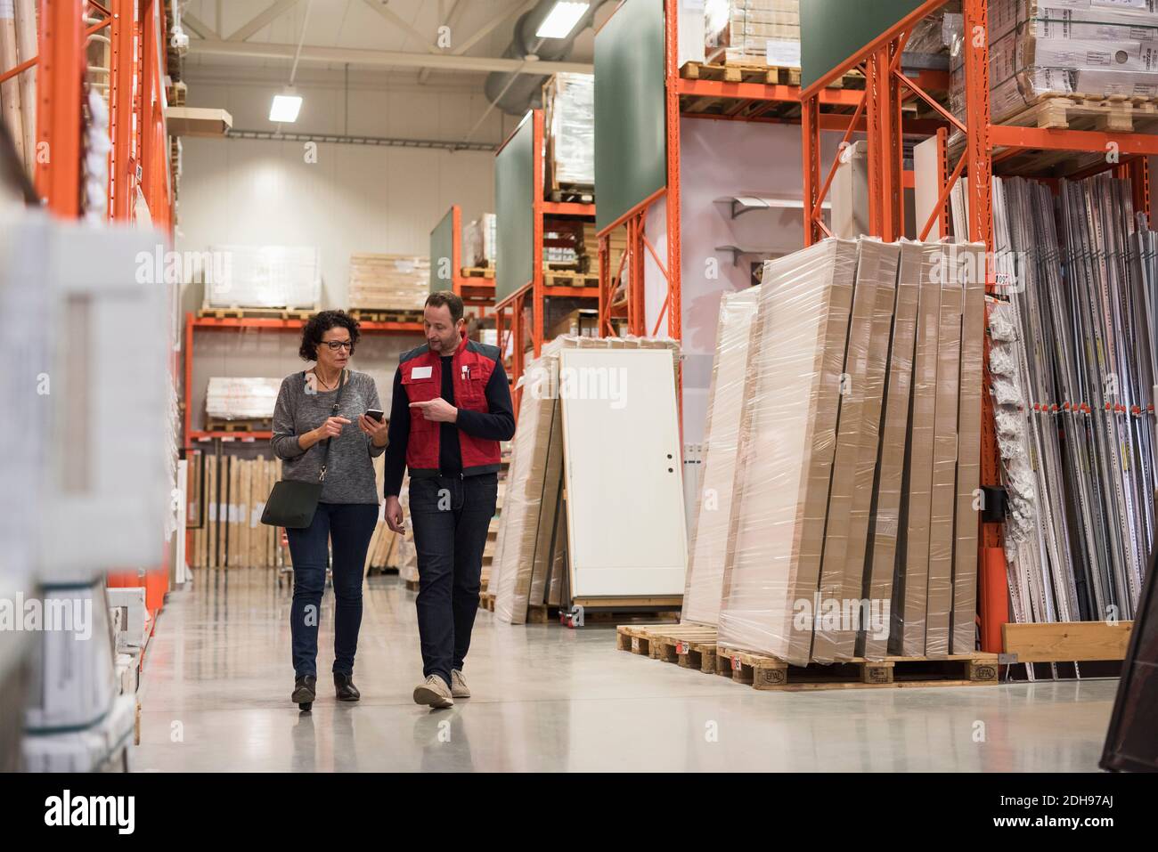 Salesman and female customer using smart phone while walking in ...