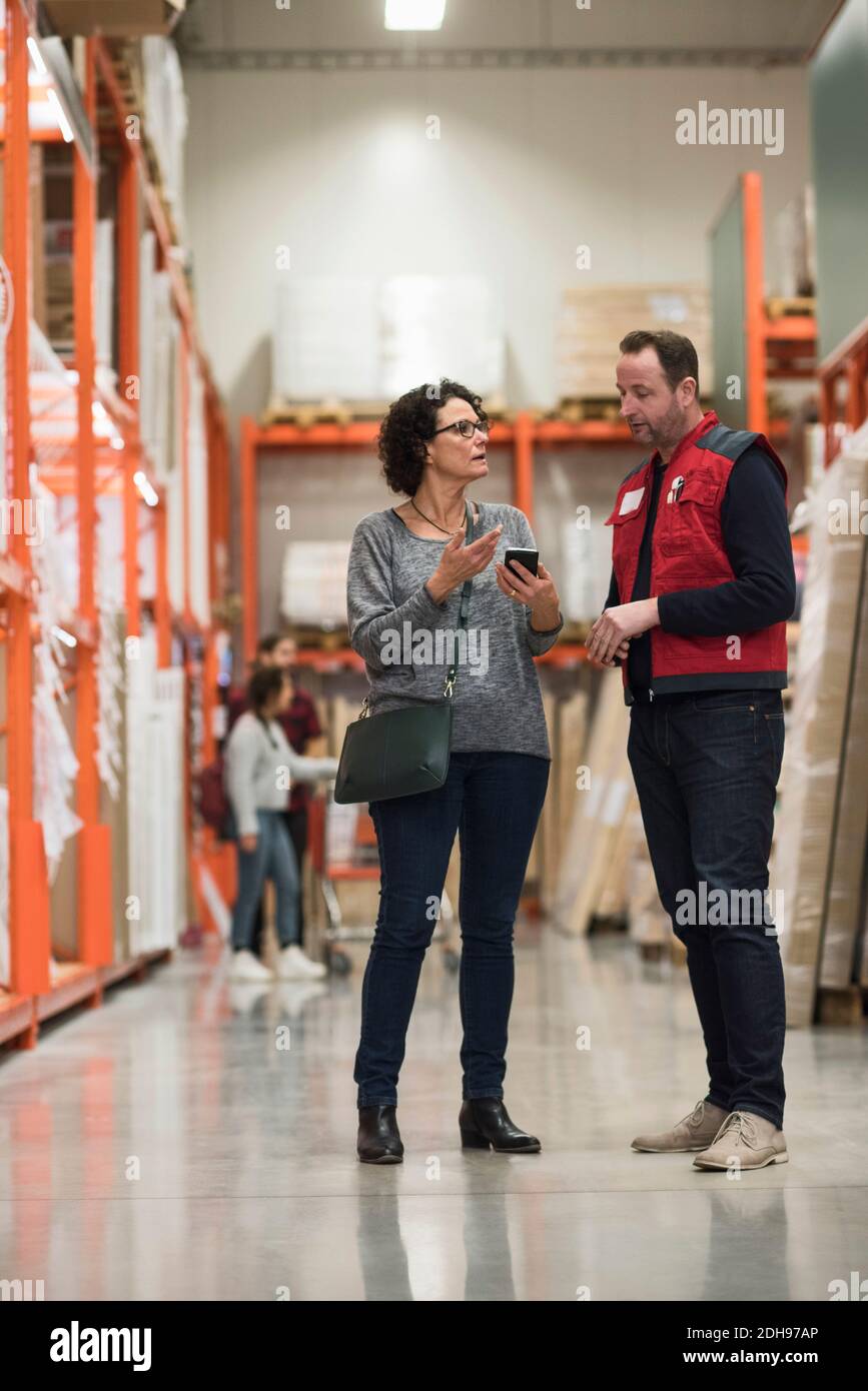 Female customer talking to salesman while holding smart phone in ...