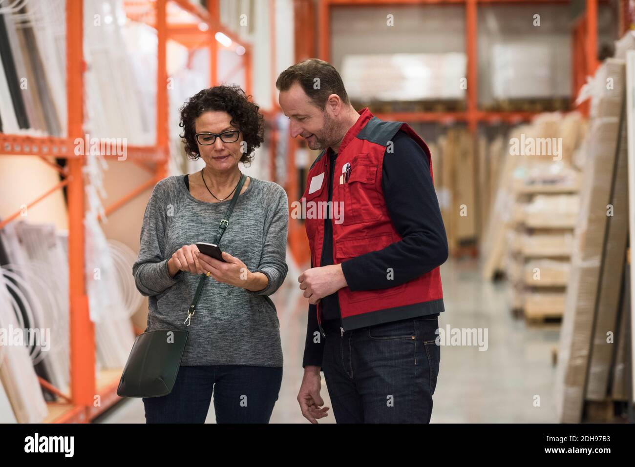 Salesman and female customer using smart phone in hardware store Stock ...