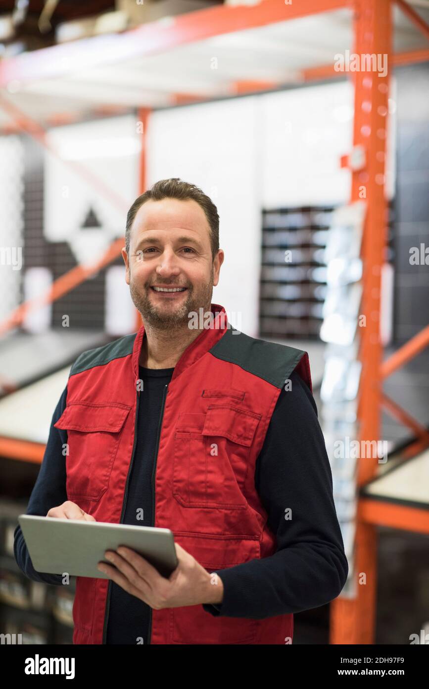 Portrait of happy salesman holding digital tablet while standing in ...