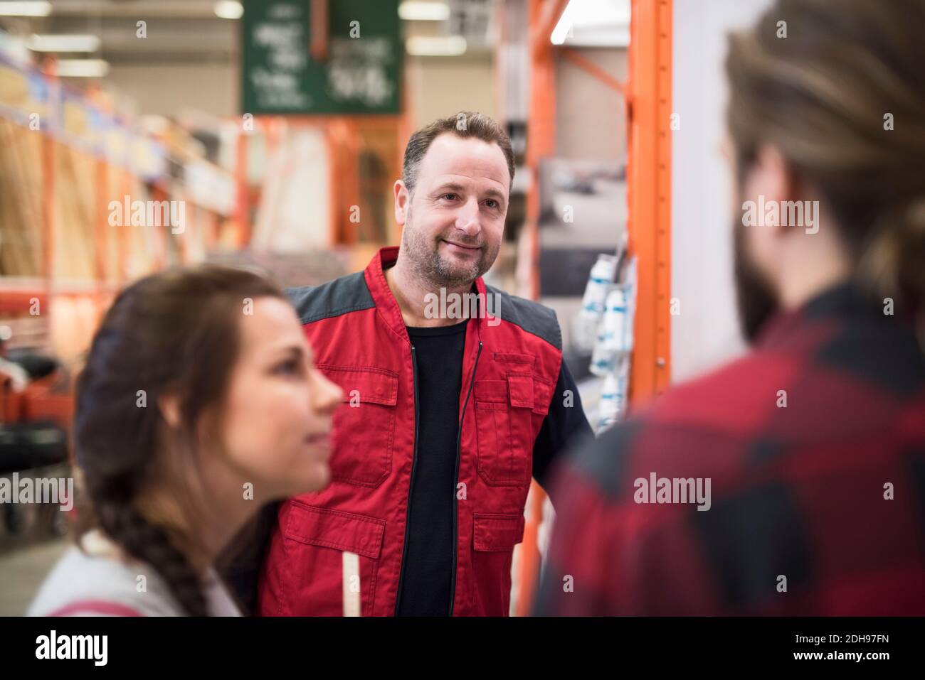 Smiling salesman looking at couple in hardware store Stock Photo - Alamy