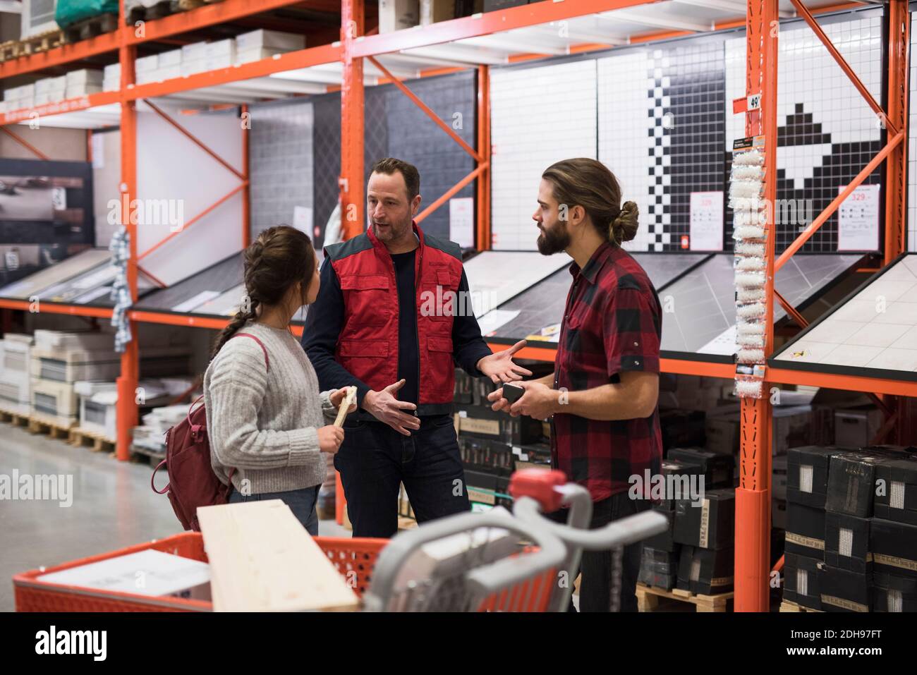 Salesman discussing with couple by shelves at hardware store Stock ...