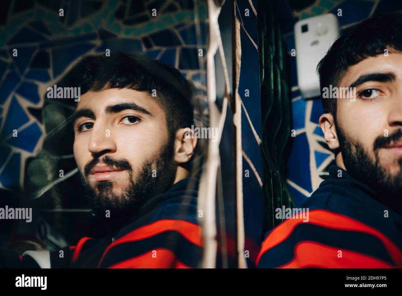 Young man looking through mirror reflection of bathroom at restaurant ...