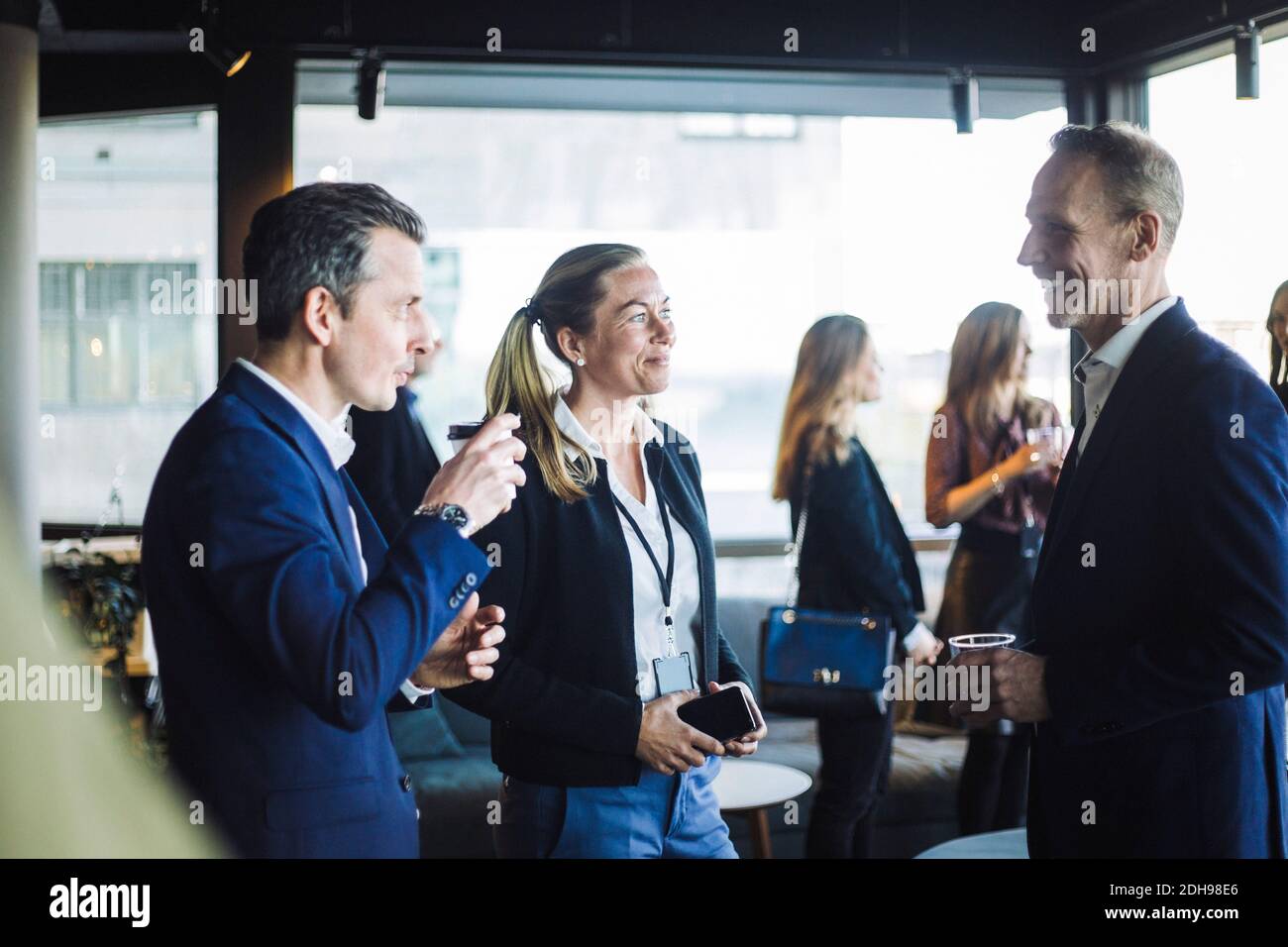 Male and female colleagues discussing while standing at workplace Stock ...
