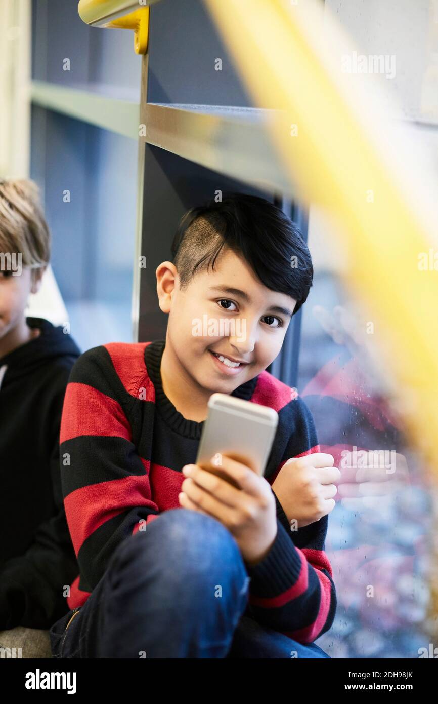Portrait of smiling boy holding smart phone in middle school Stock ...