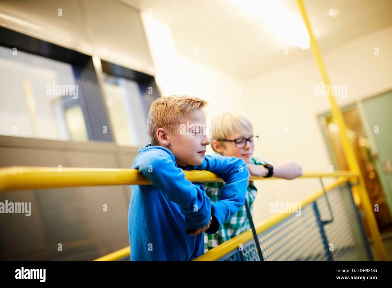 Boys leaning on raining in school building Stock Photo - Alamy