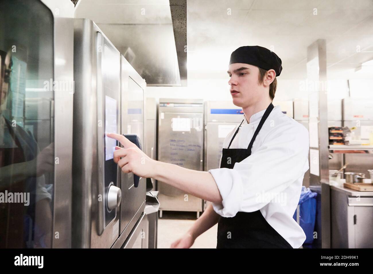 Male chef student operating microwave oven at cooking school Stock ...