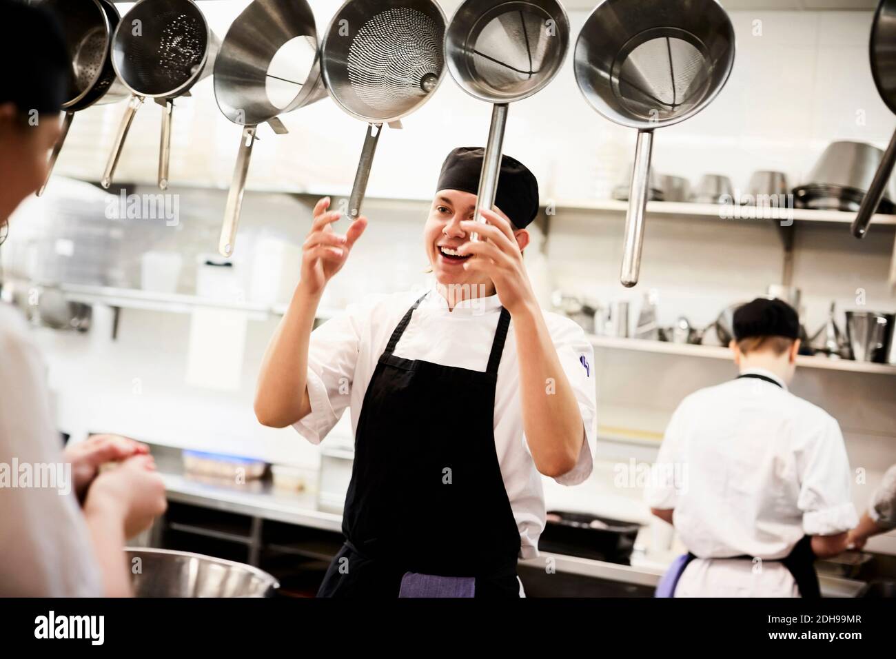 Male chef holding colanders while talking with colleague in commercial ...