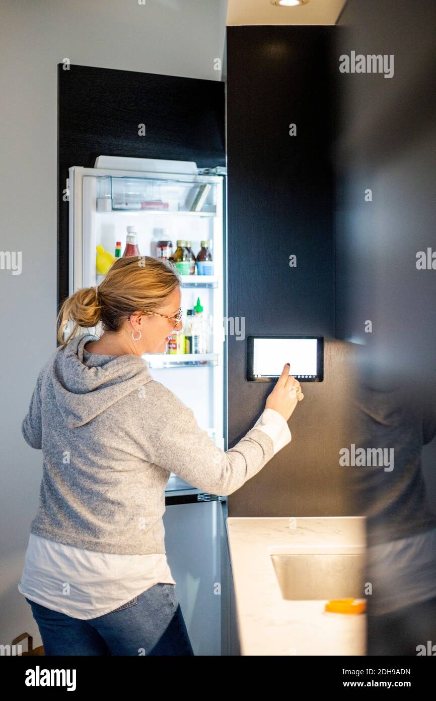 Woman using digital tablet on smart refrigerator at modern home Stock ...
